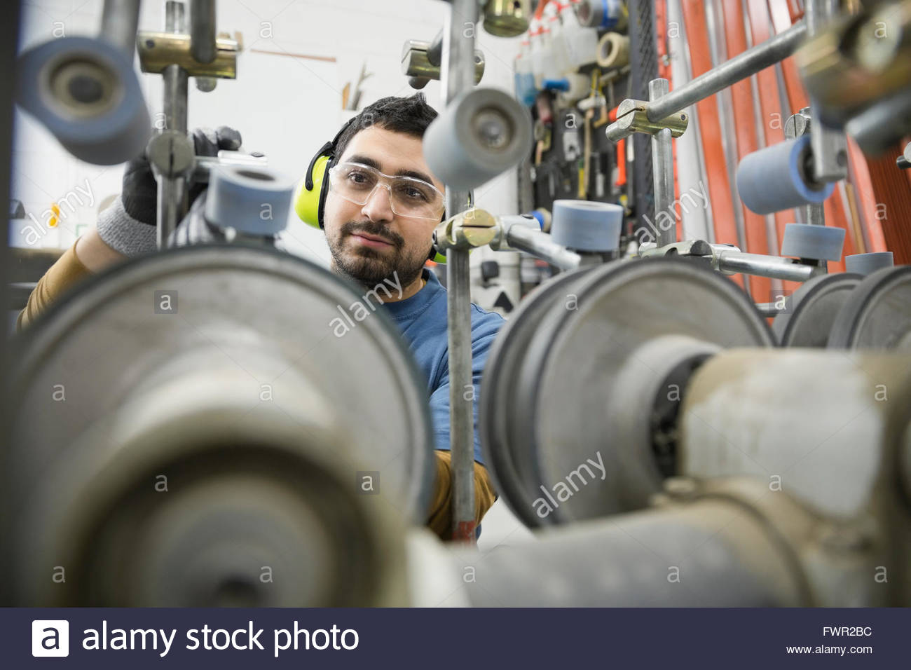 Worker adjusting machine in factory Stock Photo - Alamy