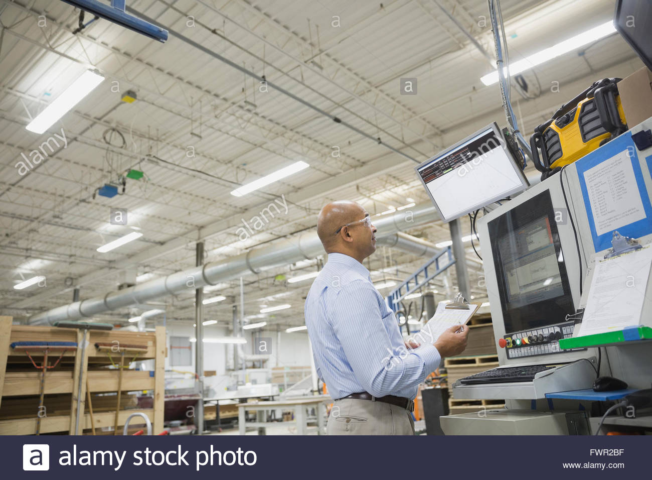 Manager looking at computer monitor in factory Stock Photo - Alamy