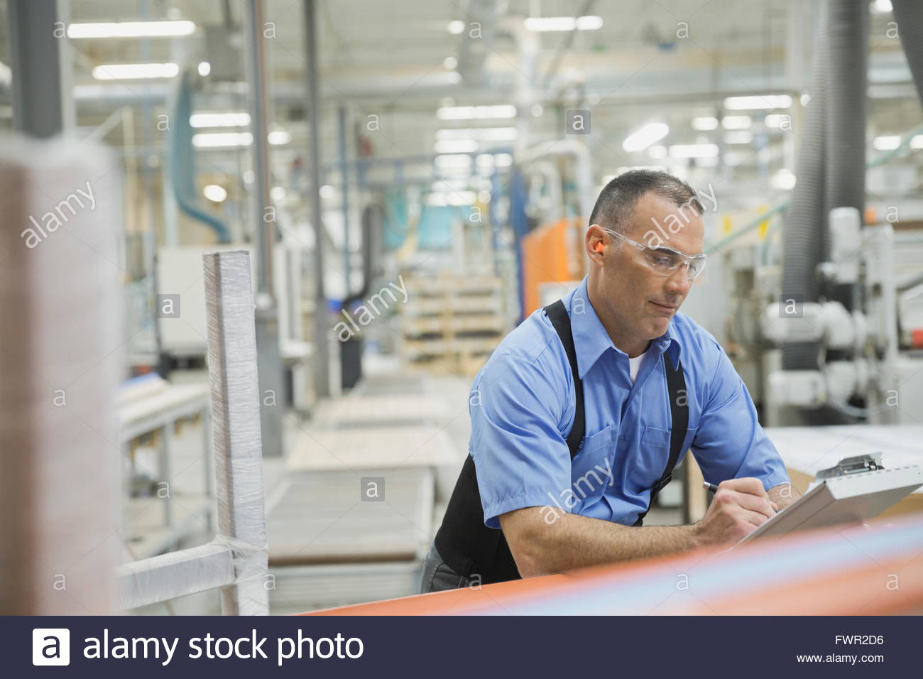 Worker writing on clipboard in factory Stock Photo - Alamy