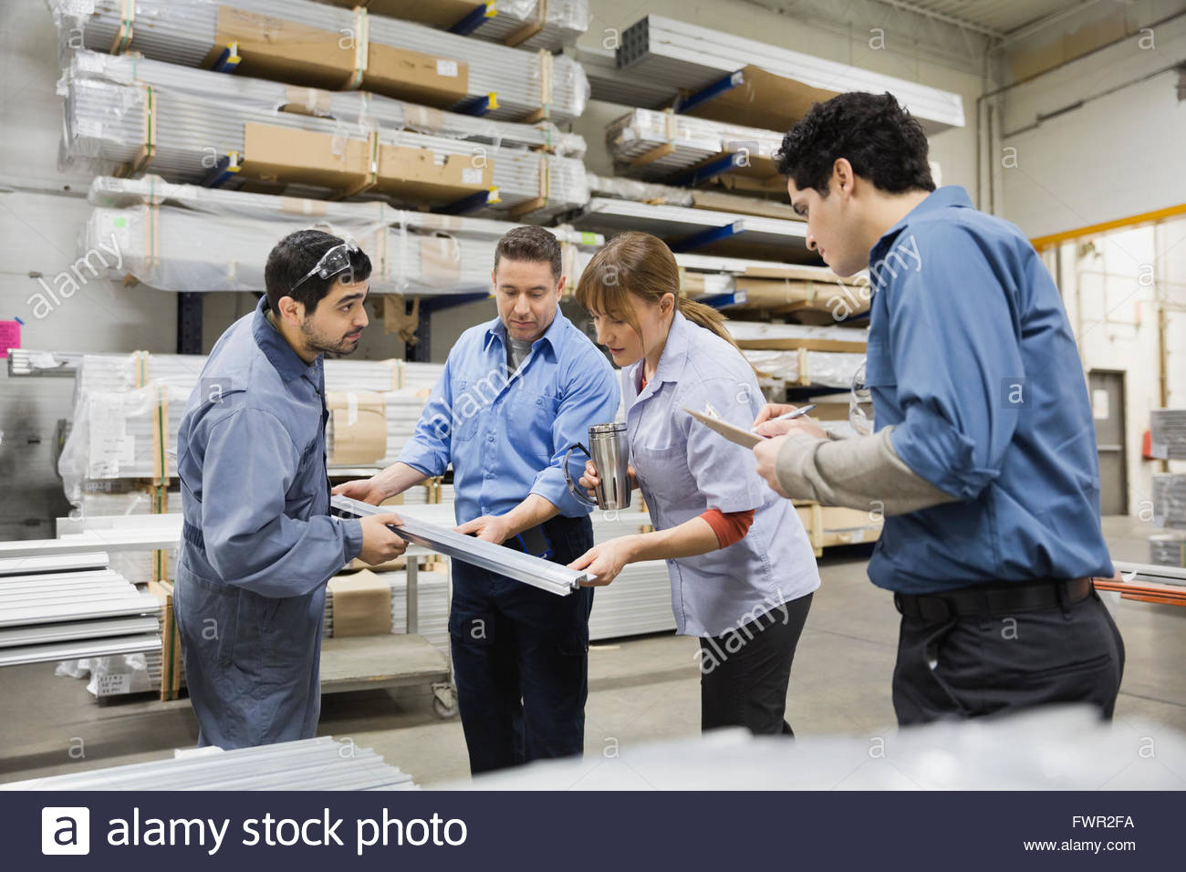 Workers examining metal parts in warehouse Stock Photo - Alamy