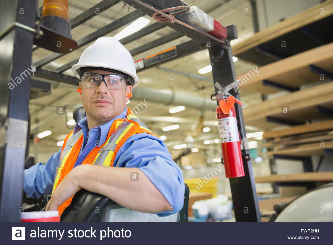 Manual worker driving forklift in warehouse Stock Photo - Alamy