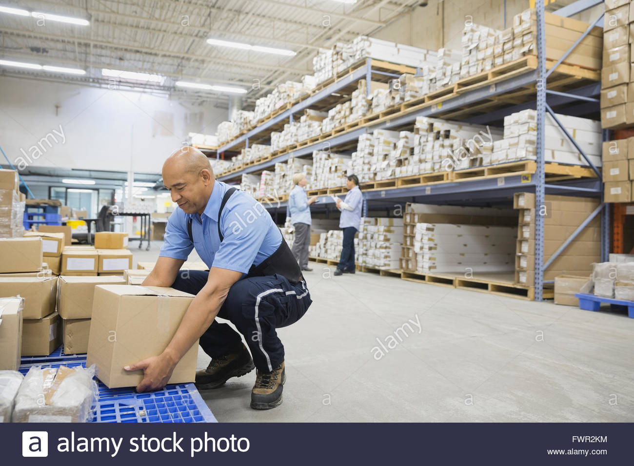 Worker lifting cardboard boxes in warehouse Stock Photo, Royalty Free ...