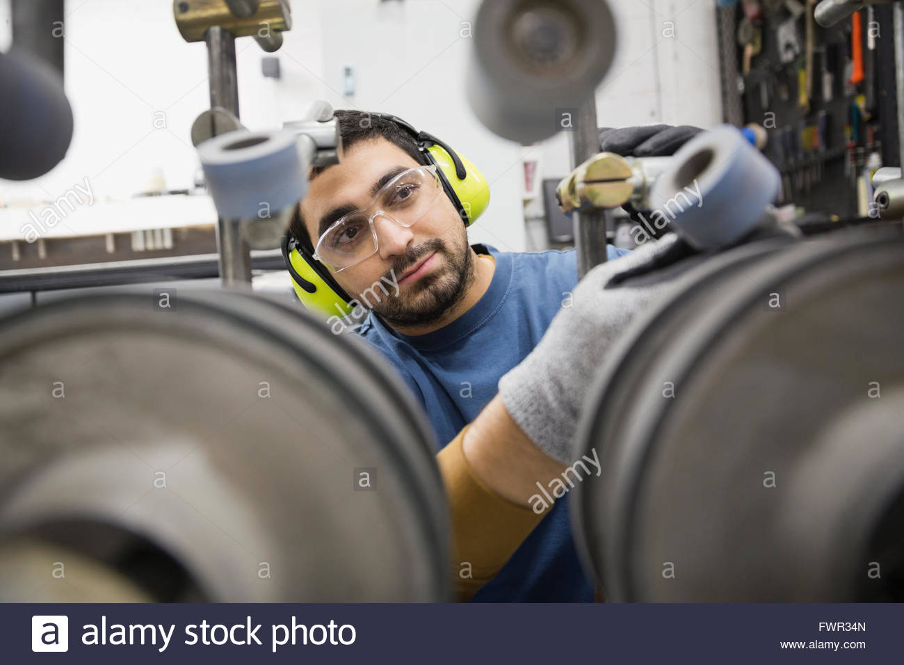 Worker adjusting machine in factory Stock Photo - Alamy