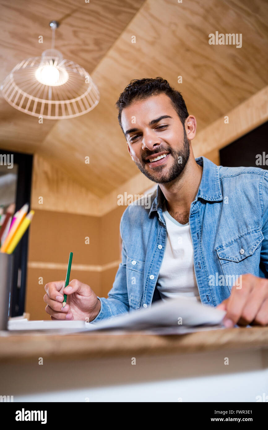 Smiling man in office writing in a notepad Stock Photo - Alamy