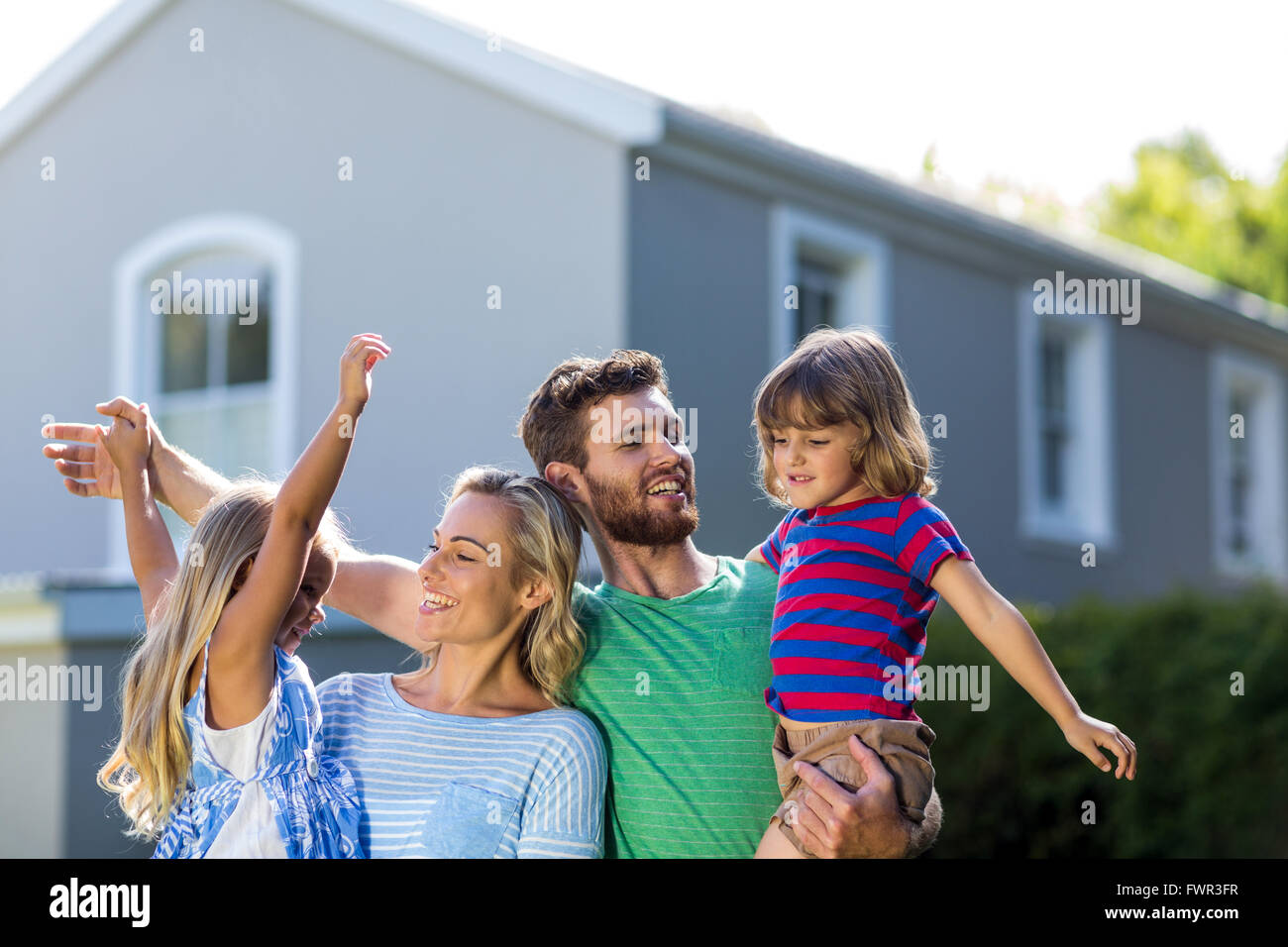 Parents carrying children with arms raised Stock Photo - Alamy