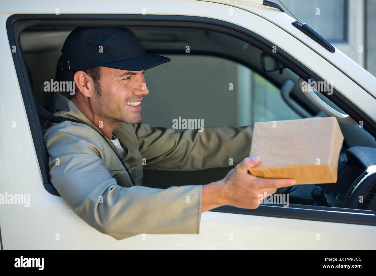Smiling delivery man sitting in his van Stock Photo - Alamy