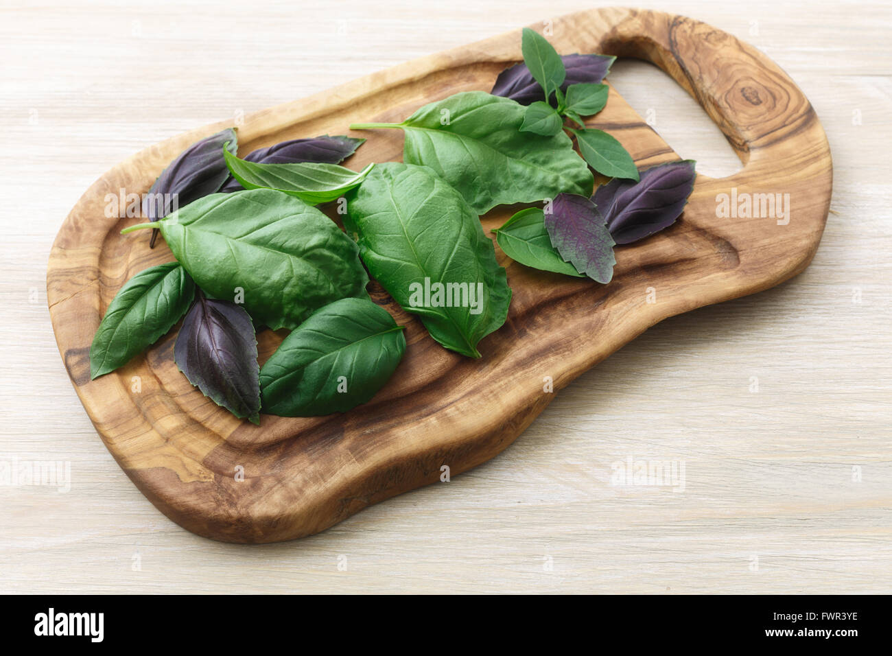 Heirloom basil on olive wood cutboard. The cultivars including Genovese ...