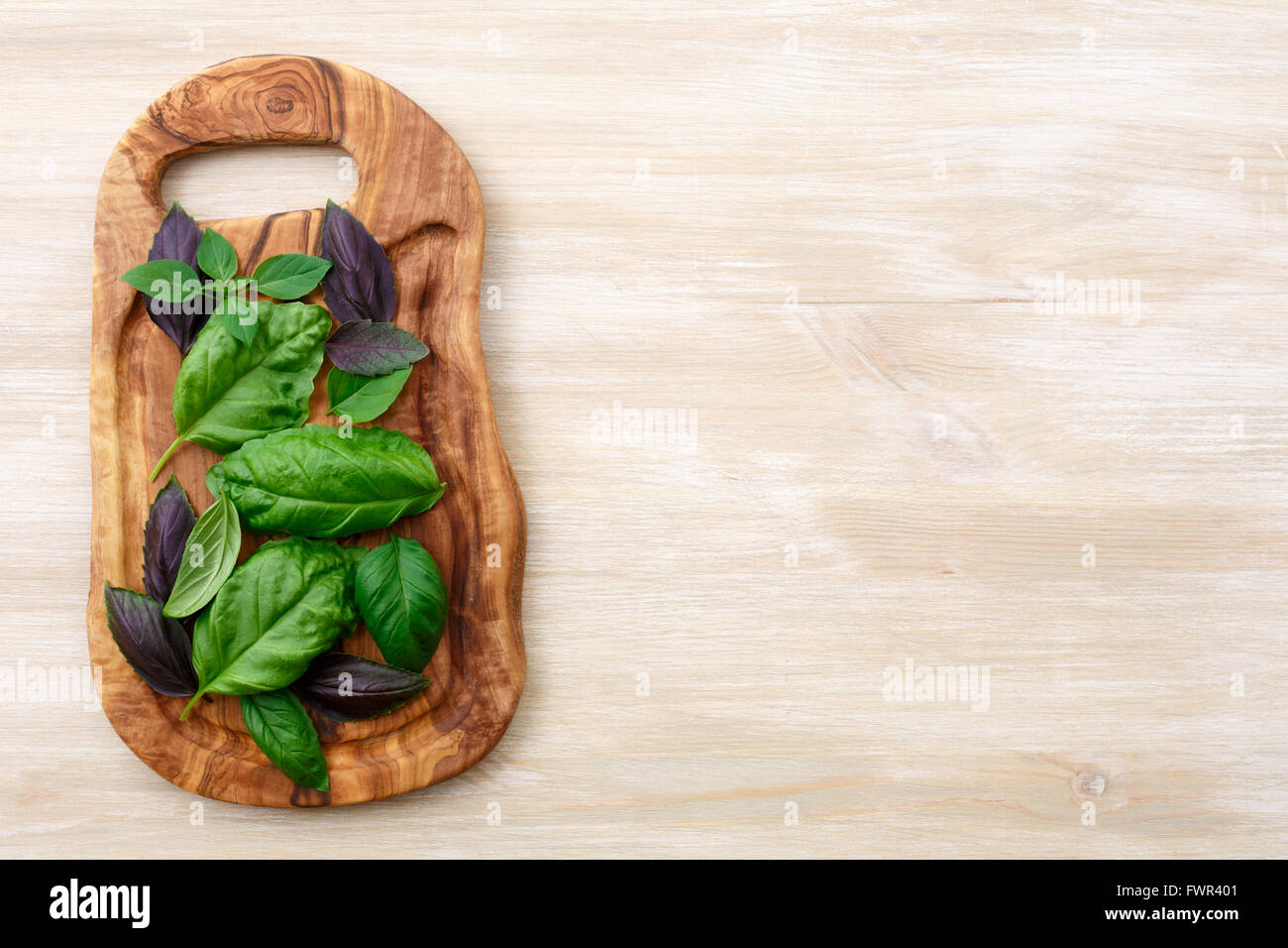 Heirloom basil on olive wood cutboard. The cultivars including Genovese ...