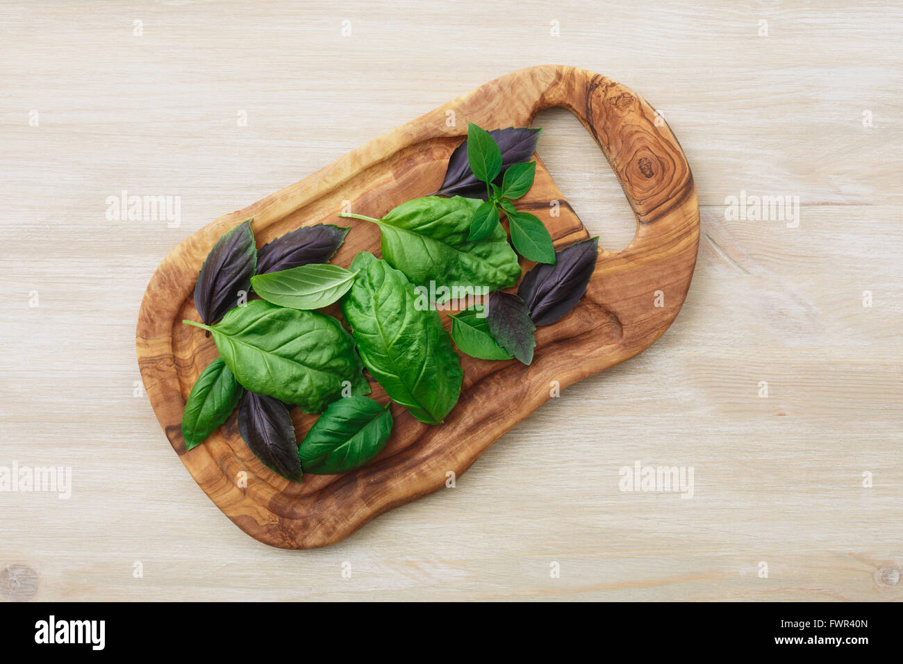 Heirloom basil on olive wood cutboard. The cultivars including Genovese ...