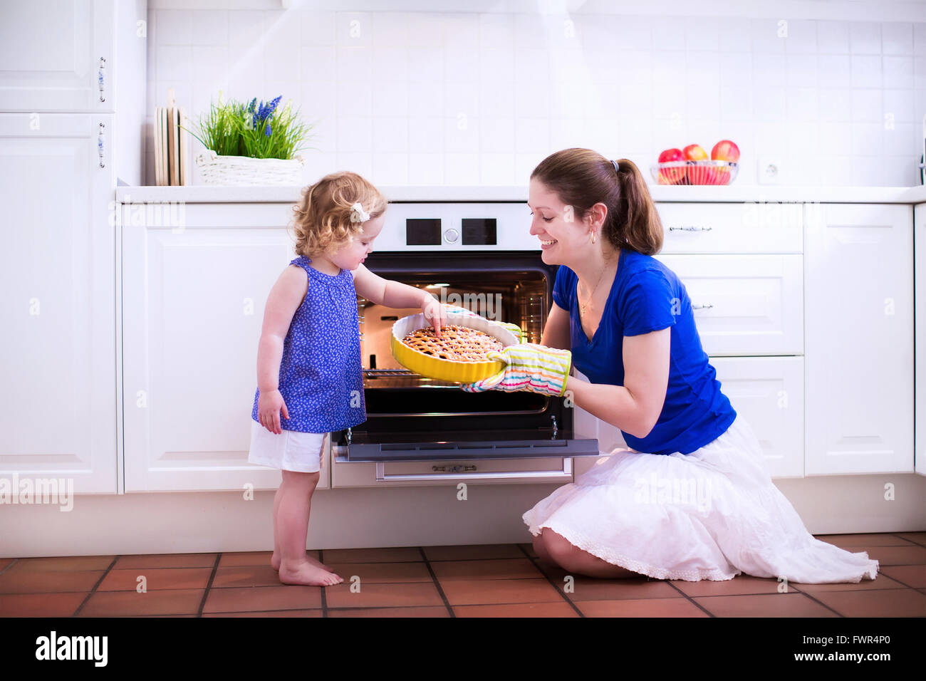 Mother and child bake a pie. Young woman and her daughter cook in a ...