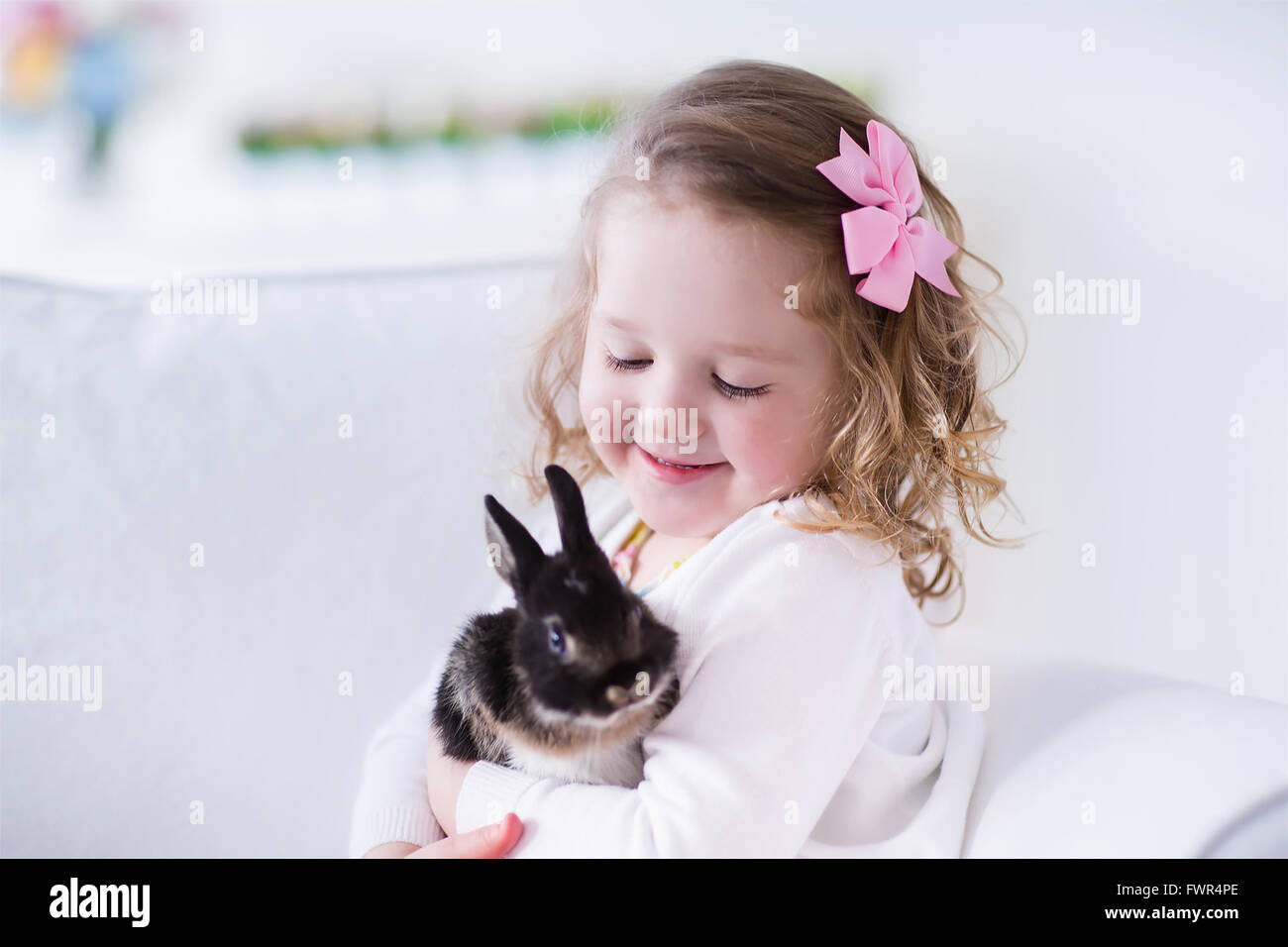 Child playing with a real rabbit. Kids play with pets. Little girl ...