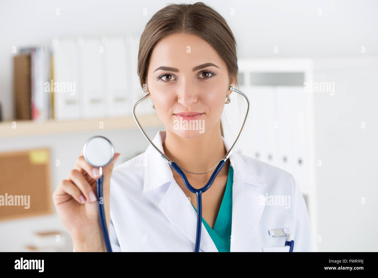 Portrait of beautiful female doctor holding stethoscope head ready to ...