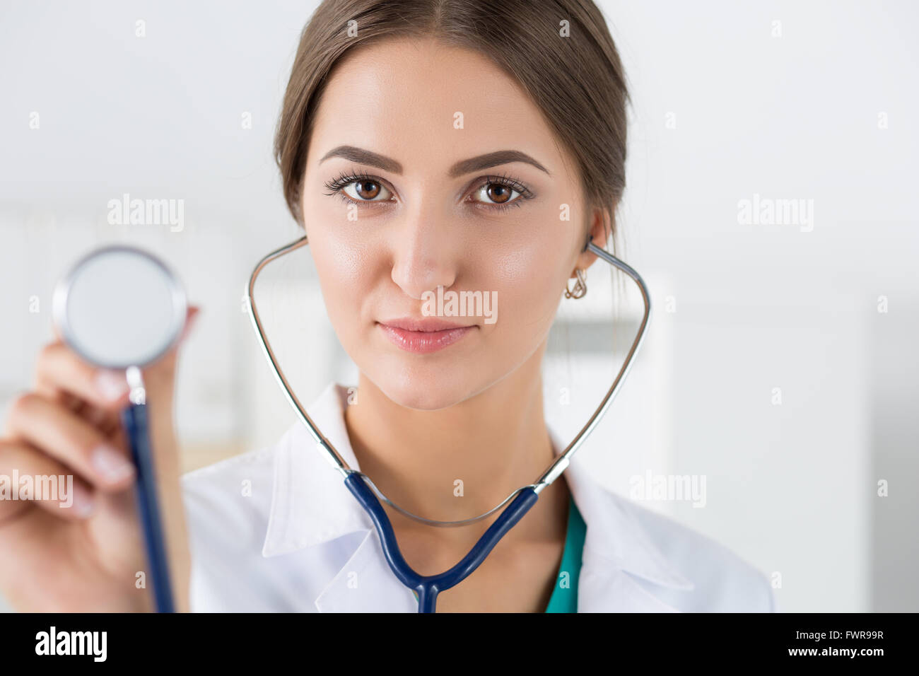 Portrait of beautiful female doctor holding stethoscope head ready to ...