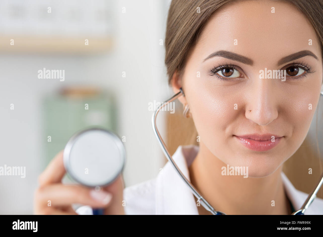Portrait of beautiful female doctor holding stethoscope head ready to ...