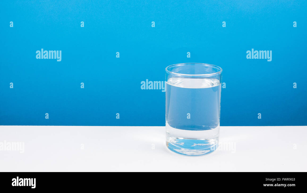 The medium cylinder glass of pure mineral water on a white table Stock ...