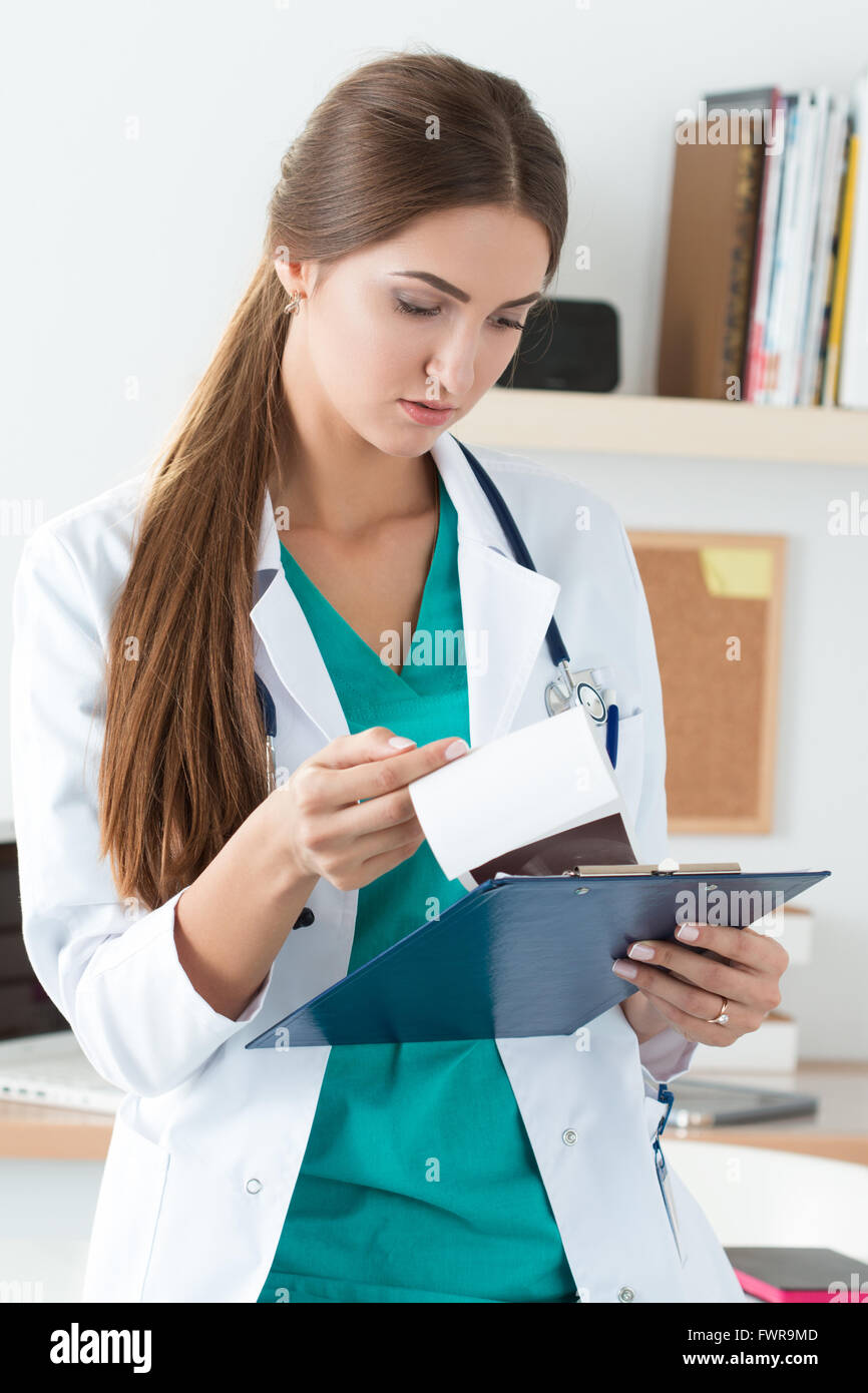 Female medicine doctor standing at her office and looking at patient's ...