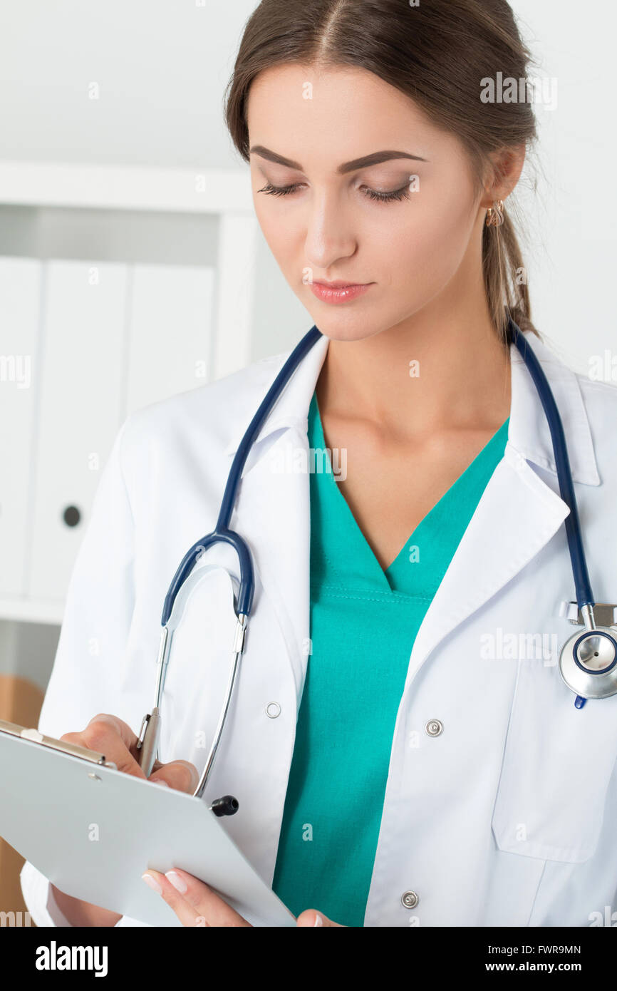 Female medicine doctor writting something standing at her office ...
