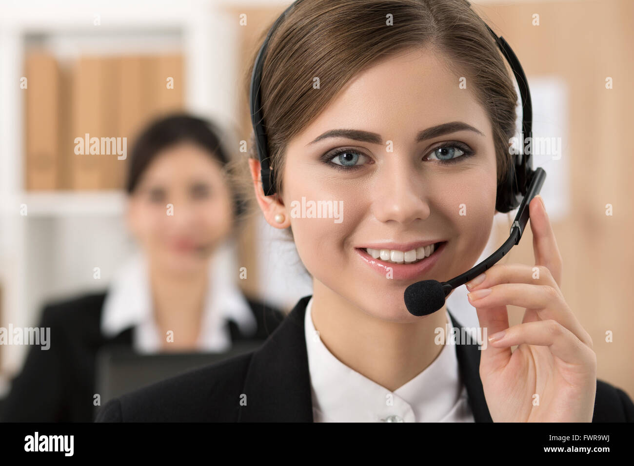 Portrait of call center worker accompanied by her team. Smiling ...