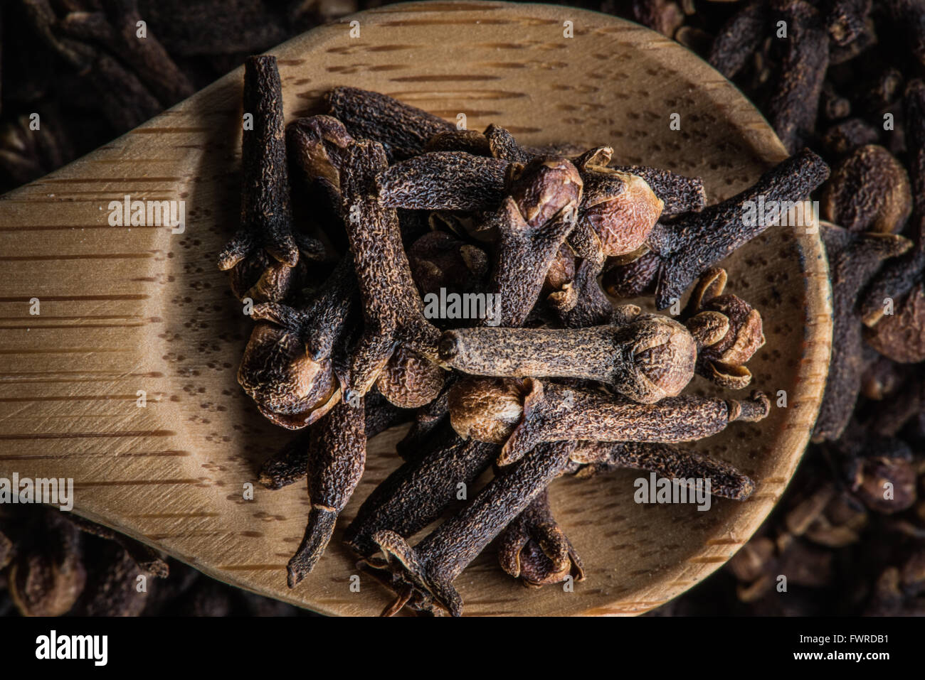 Wooden spoon with cloves in a pile of cloves Stock Photo - Alamy