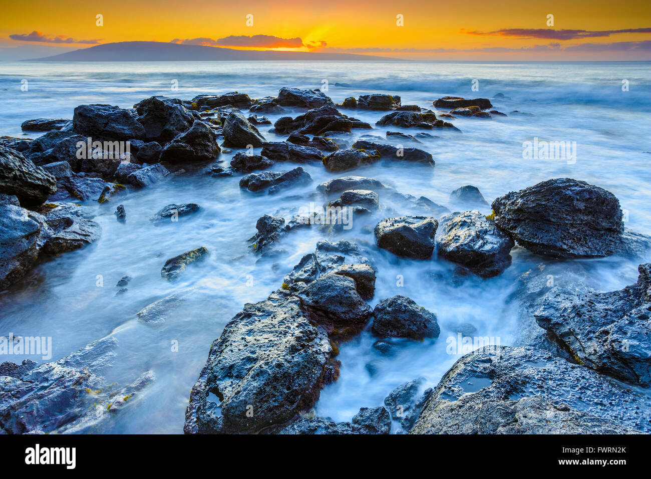 waves breaking on rocky shore of Maui at dawn with Lanai view in ...