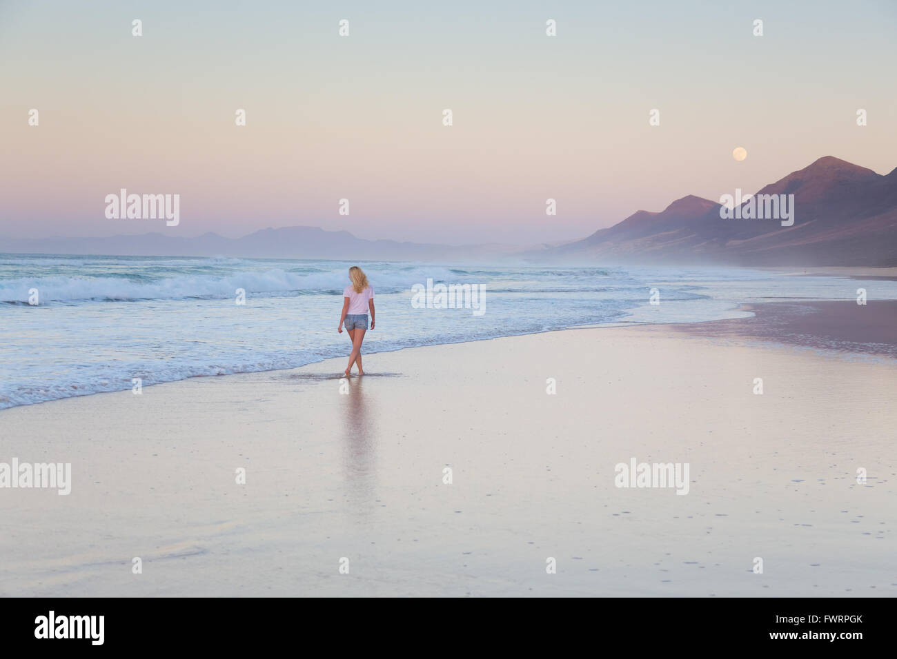 Lady walking on sandy beach in sunset Stock Photo - Alamy
