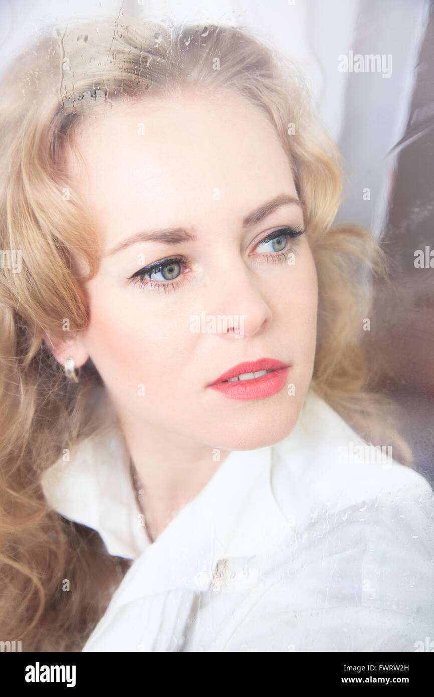 Portrait of a sad beautiful woman near the window on a rainy day Stock ...