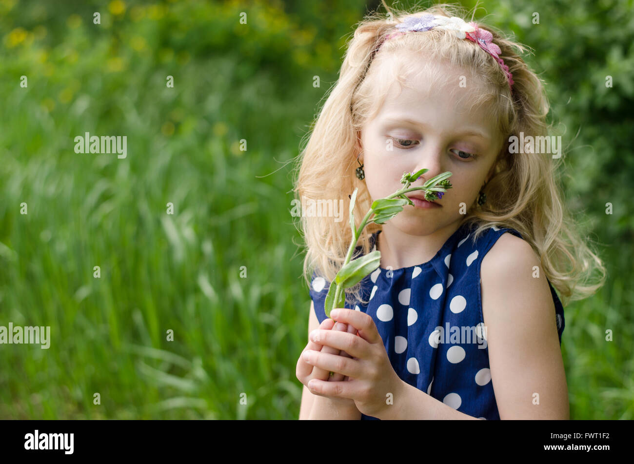 portrait of blond sad girl smelling flowers Stock Photo - Alamy