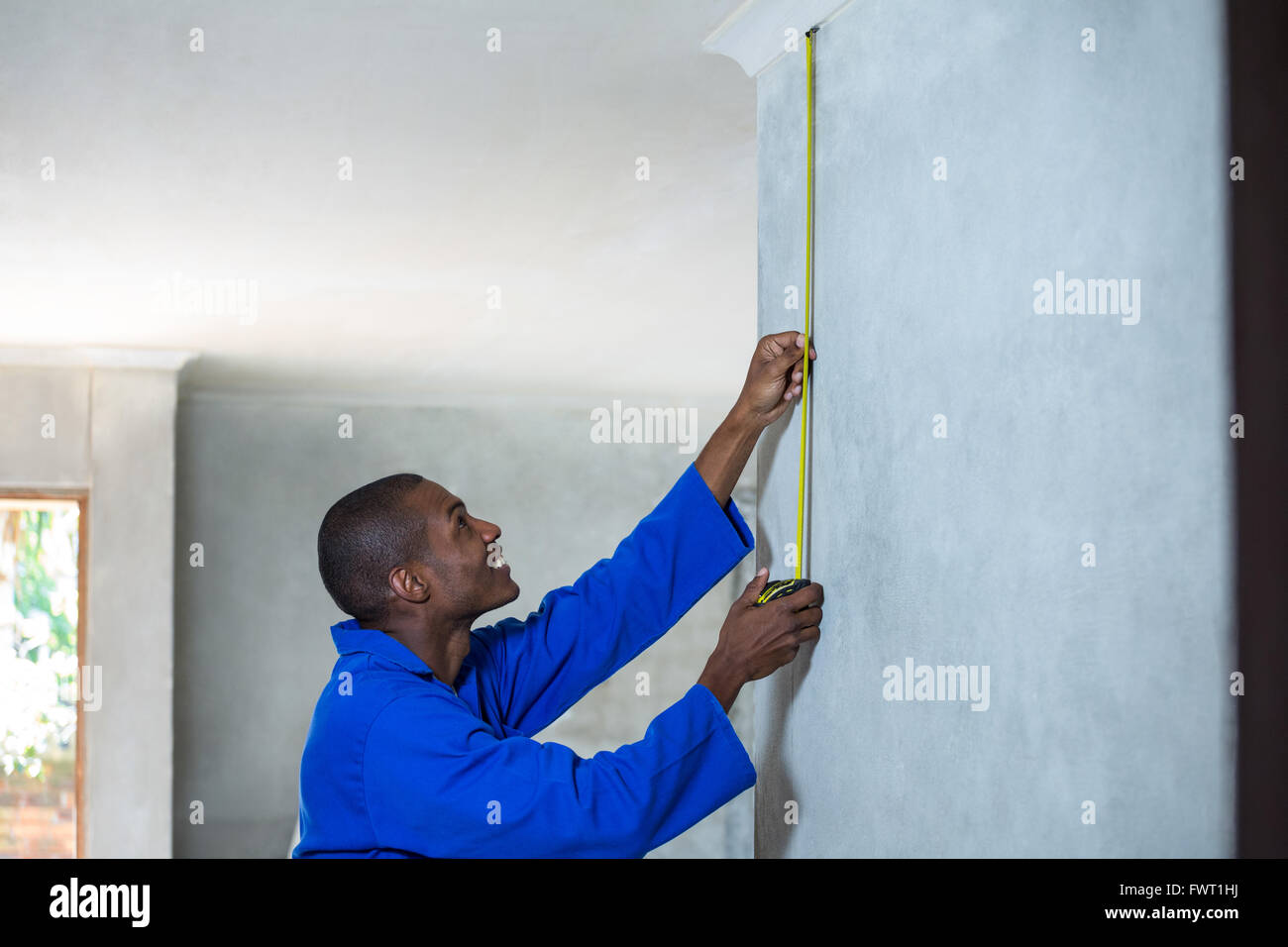 Handyman measuring a wall Stock Photo - Alamy