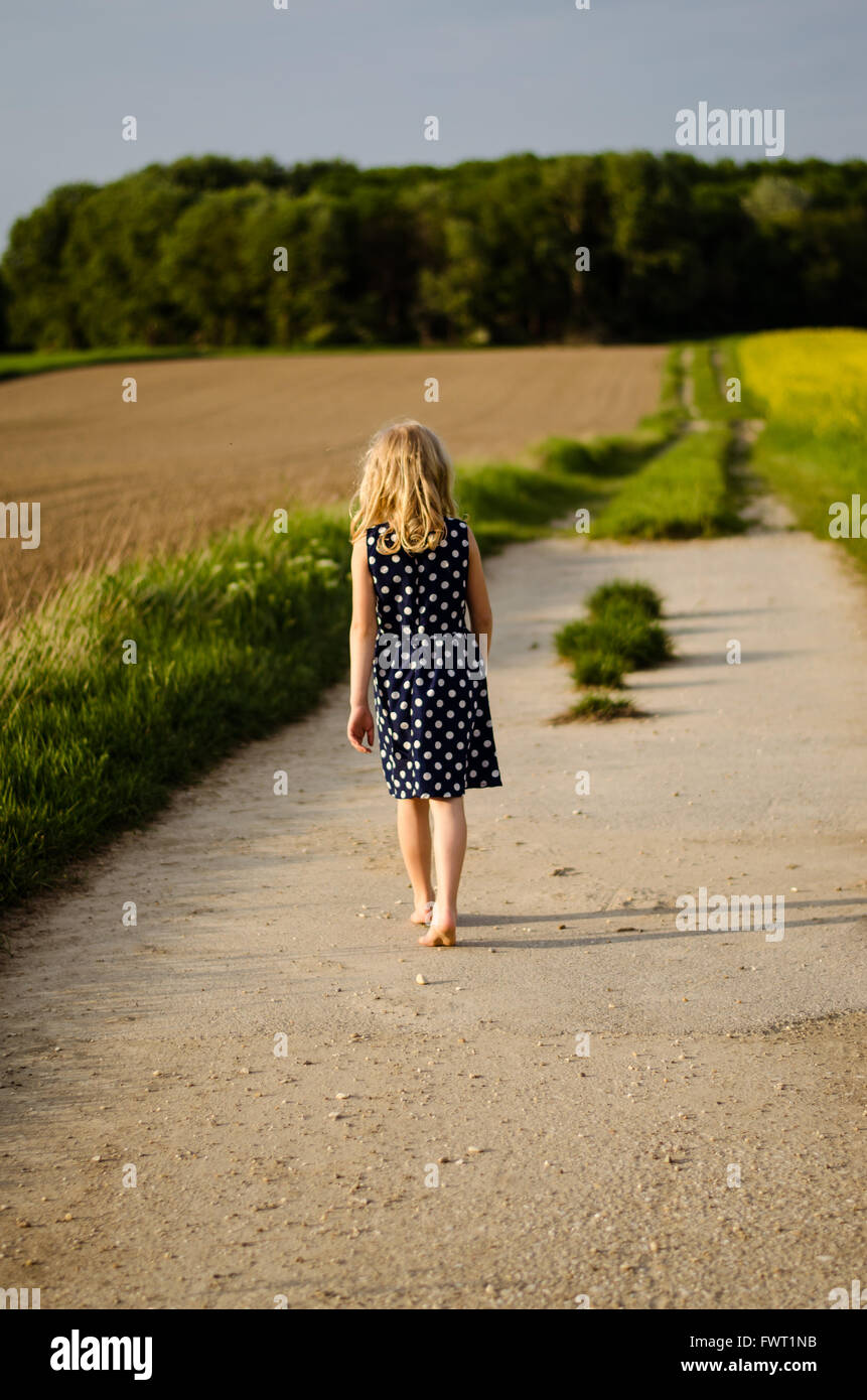 blond girl walking in path between fields Stock Photo - Alamy