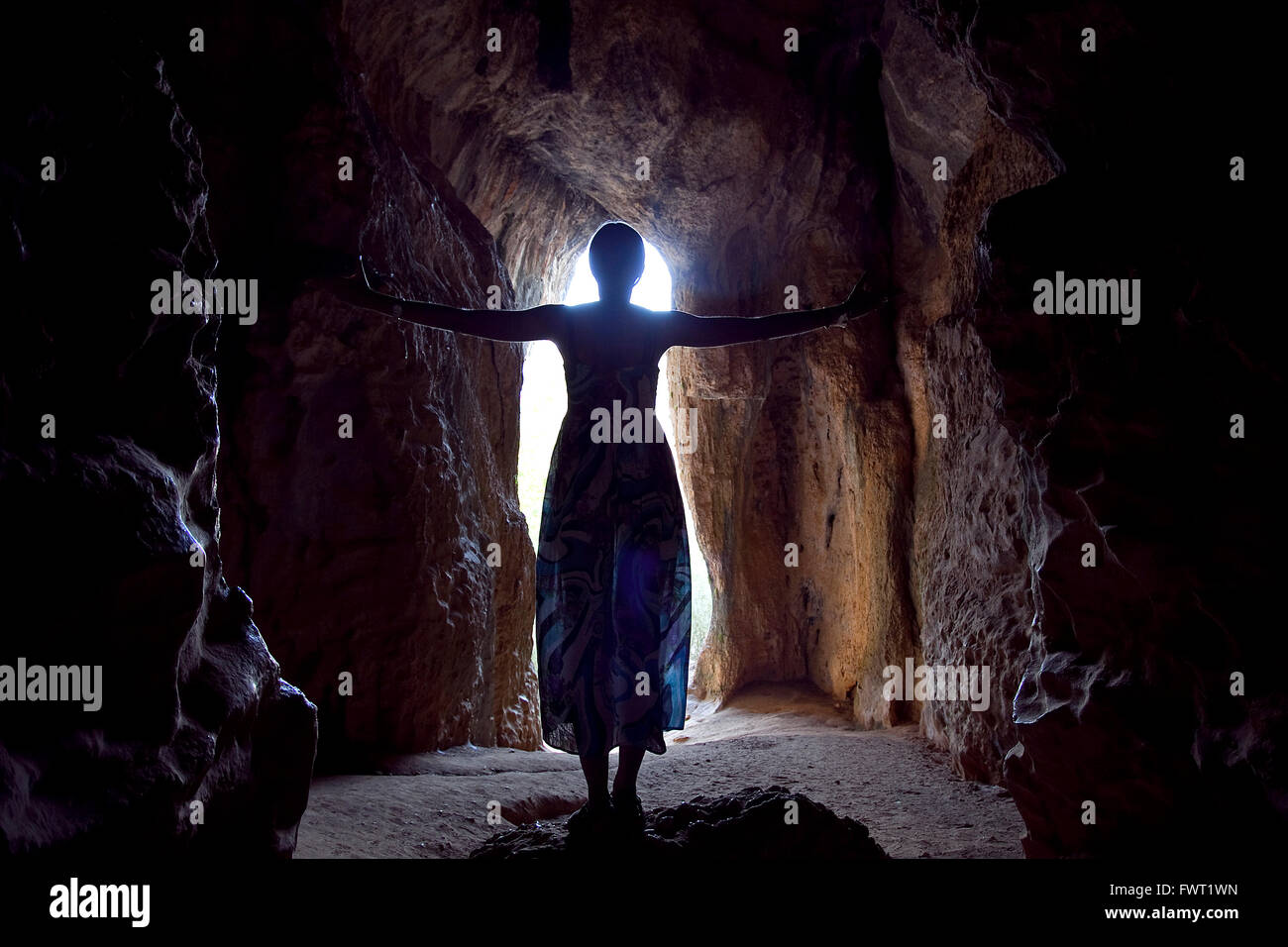 Silhouette of a woman standing at the mouth of a cave Cueva Grande ...