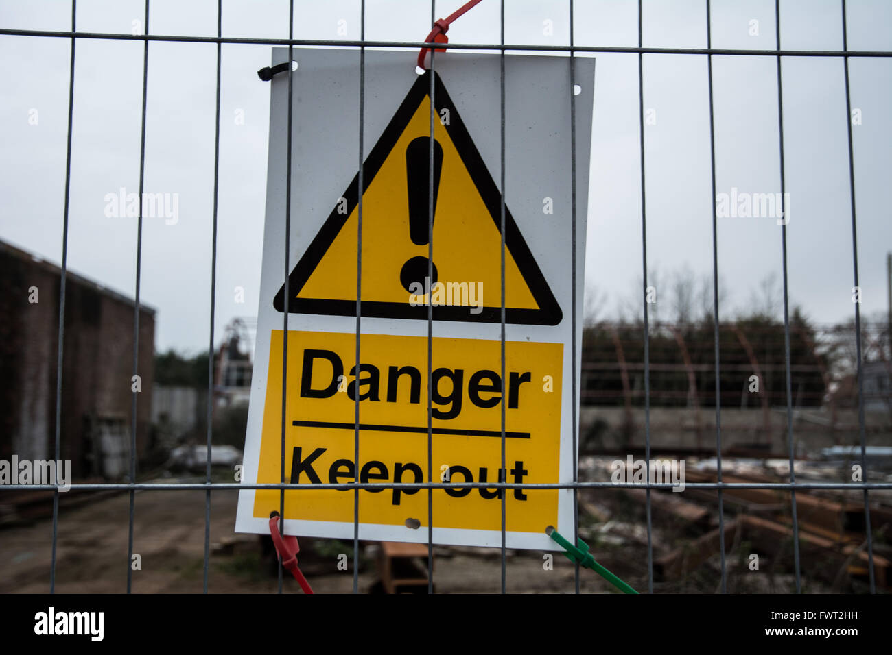 A 'Danger Keep Out' sign in front of a lot of scrap metal and abandoned ...