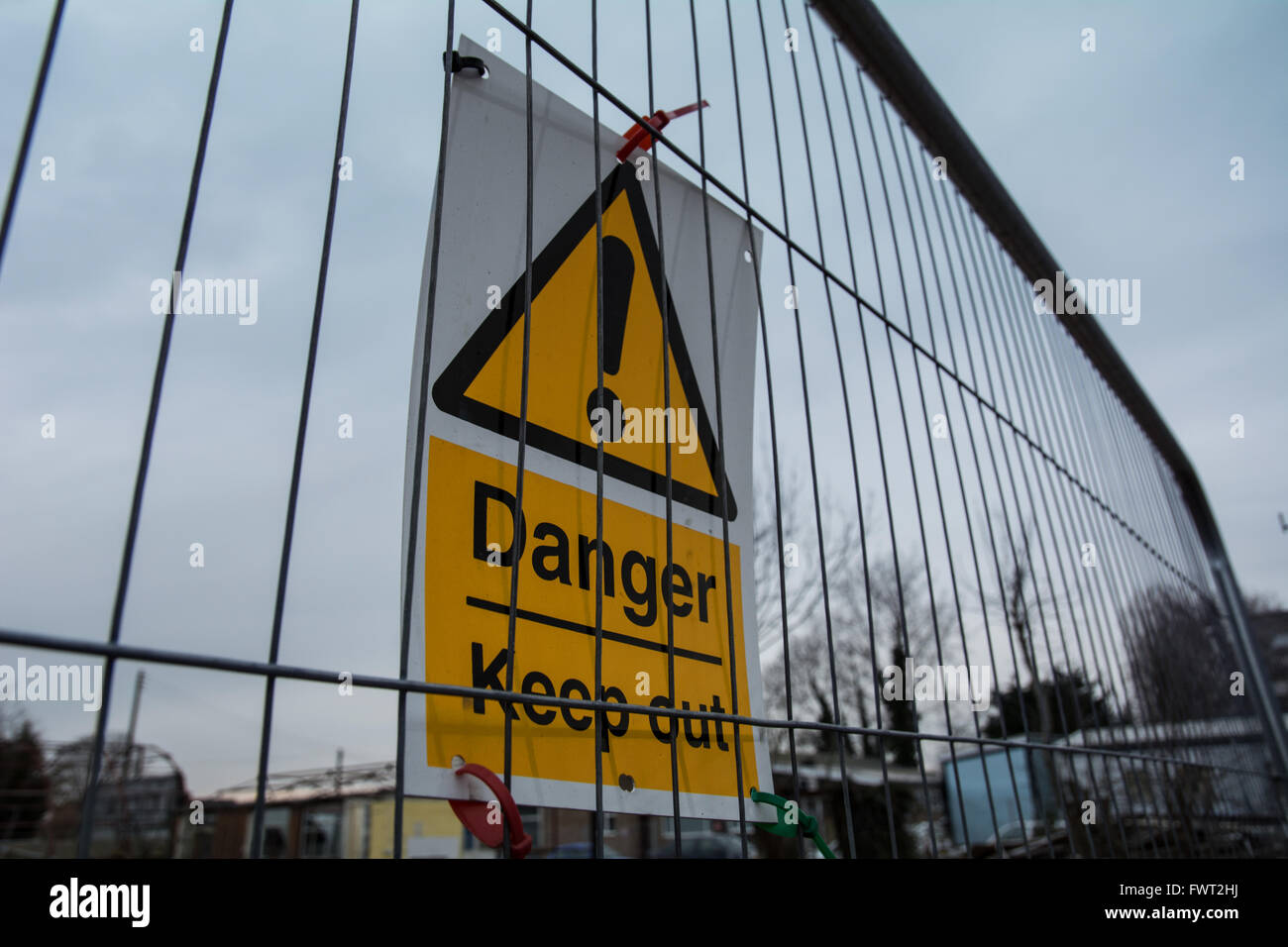 A 'Danger Keep Out' sign in front of a lot of scrap metal and abandoned ...