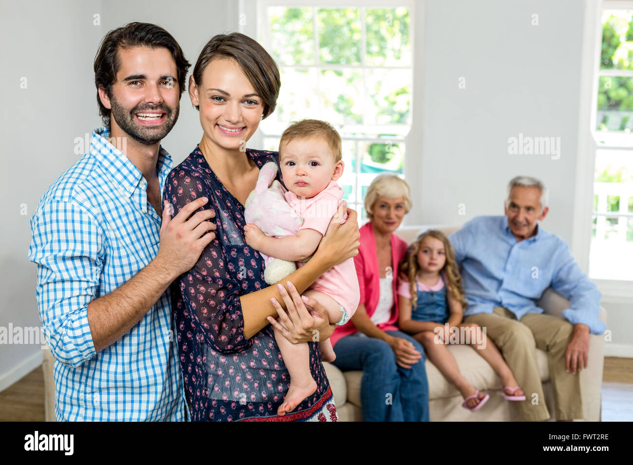 Happy family with grandparents sitting in background Stock Photo - Alamy