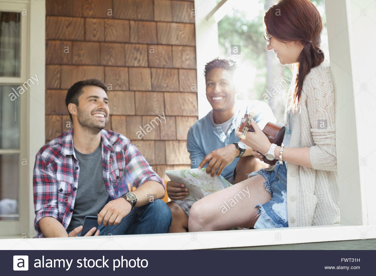 Group of friends hanging out on cabin porch Stock Photo - Alamy