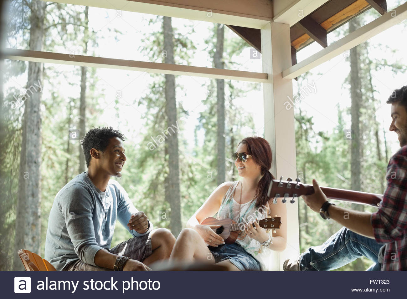 Friends playing music on cabin patio Stock Photo - Alamy