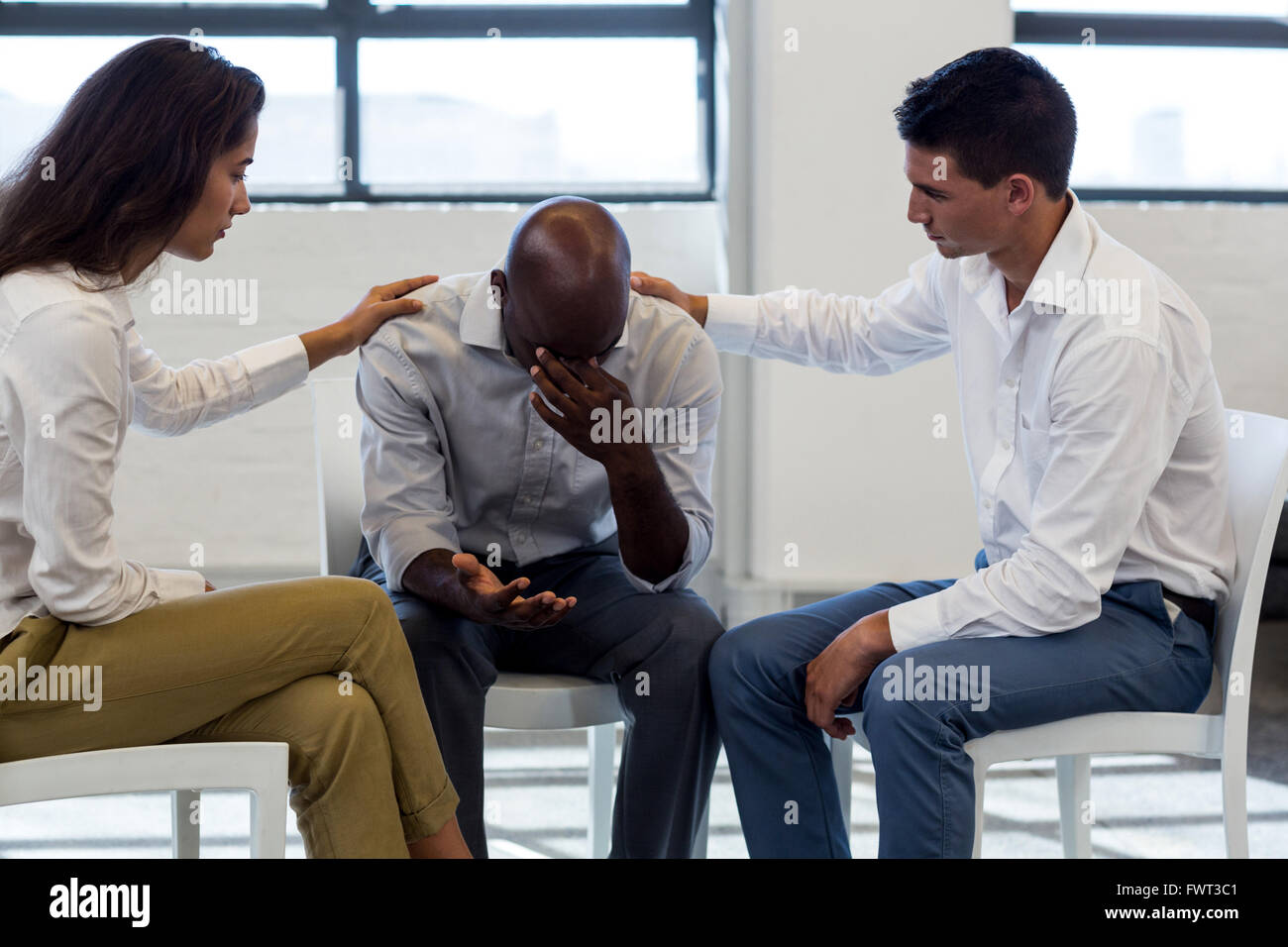 Colleagues comforting a unhappy man Stock Photo - Alamy