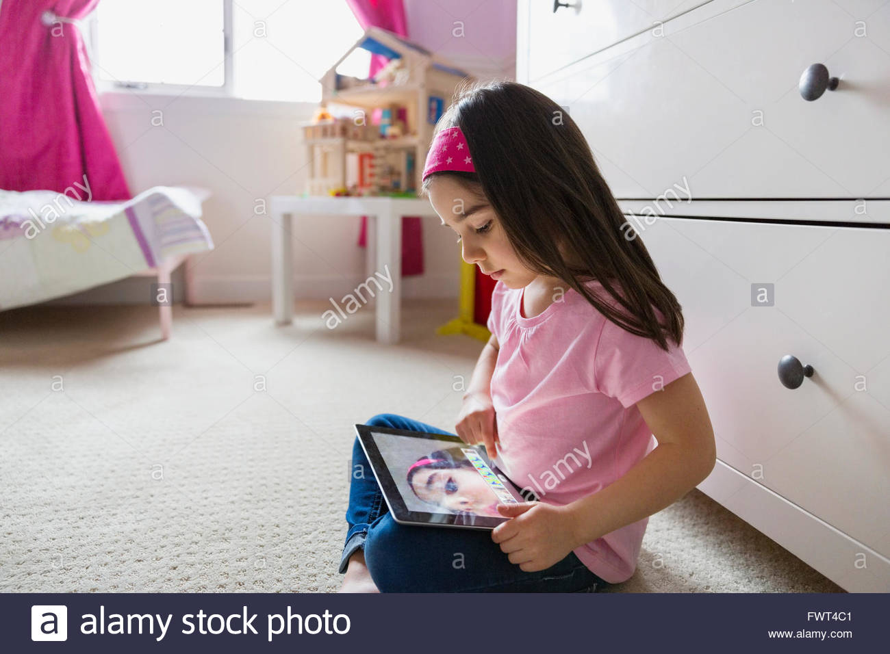 Little girl using digital tablet while sitting on floor Stock Photo - Alamy