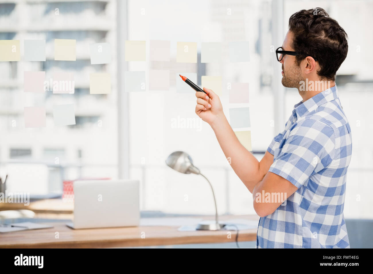 Thoughtful man reading at sticky notes on window Stock Photo - Alamy