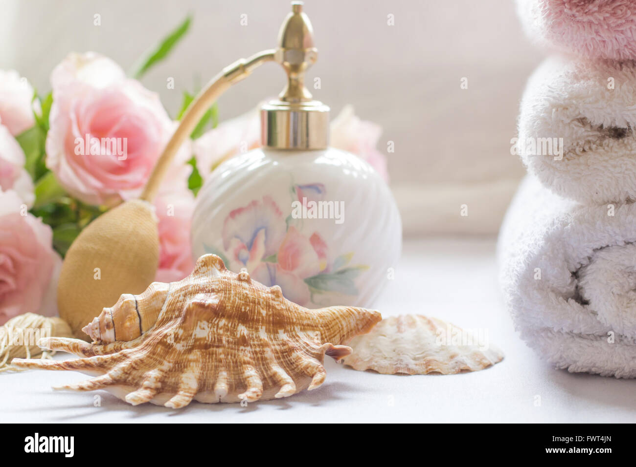 Bath arrangement with perfume bottle, folded towels and pink roses ...