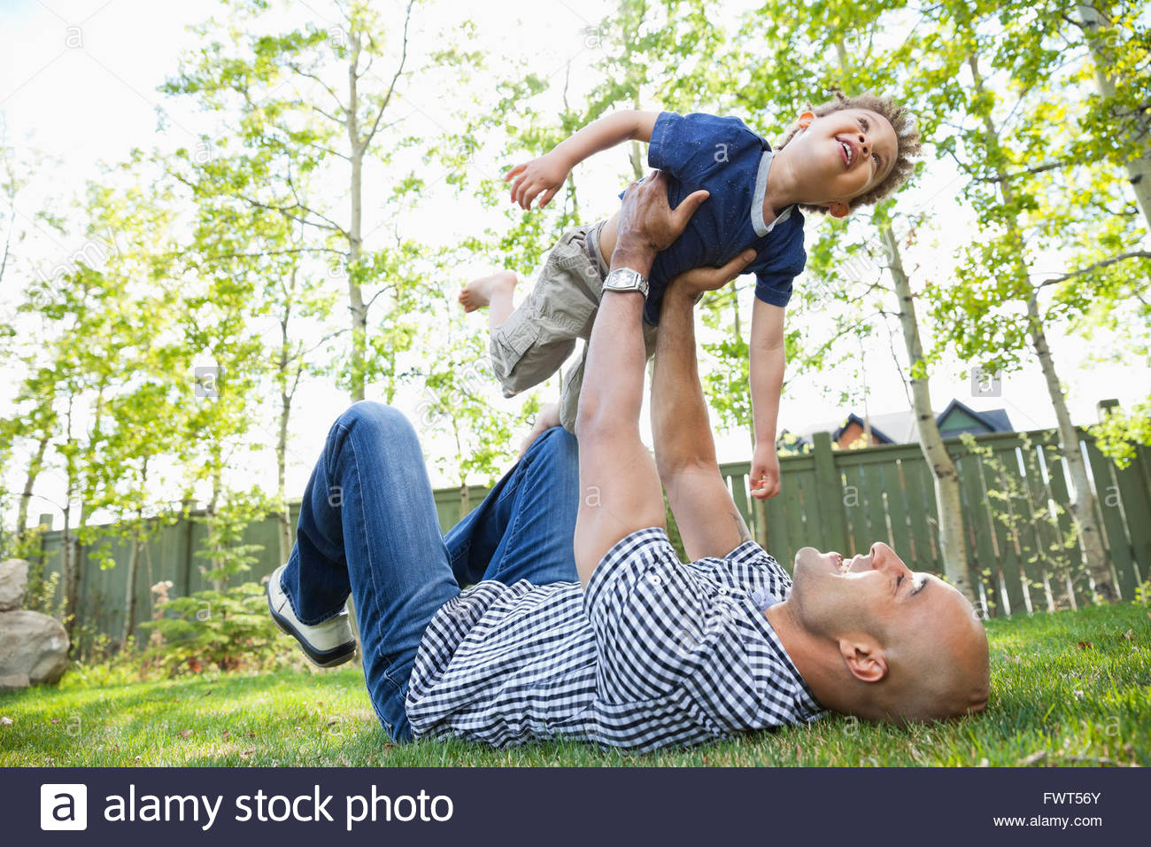 Father lifting son while lying on grass outdoors Stock Photo - Alamy