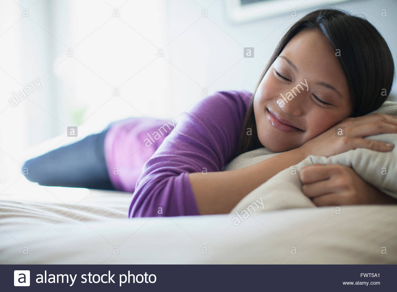 Beautiful young woman smiling while sleeping on bed Stock Photo - Alamy