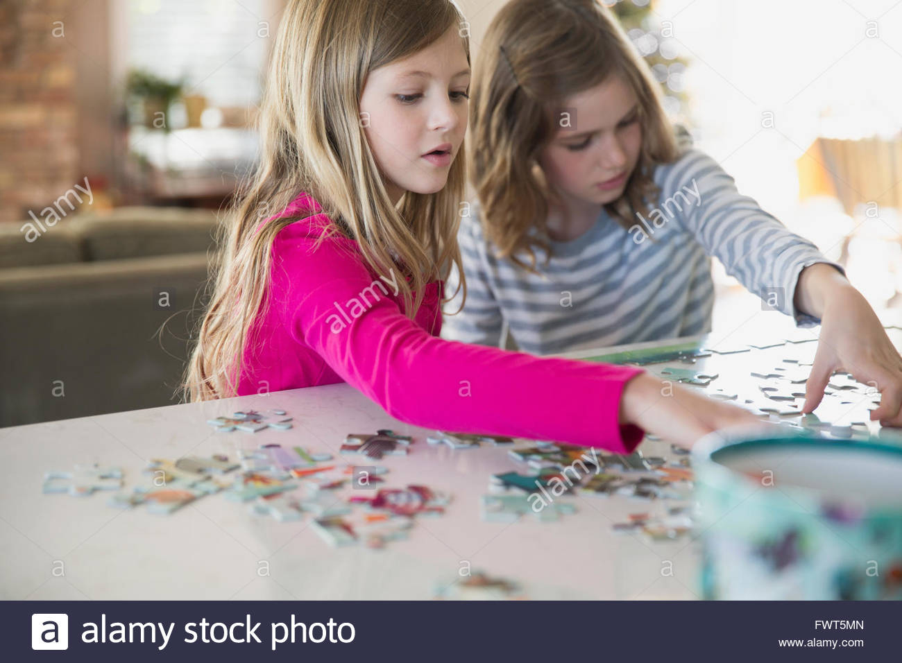 Young sisters doing jigsaw puzzle together Stock Photo - Alamy