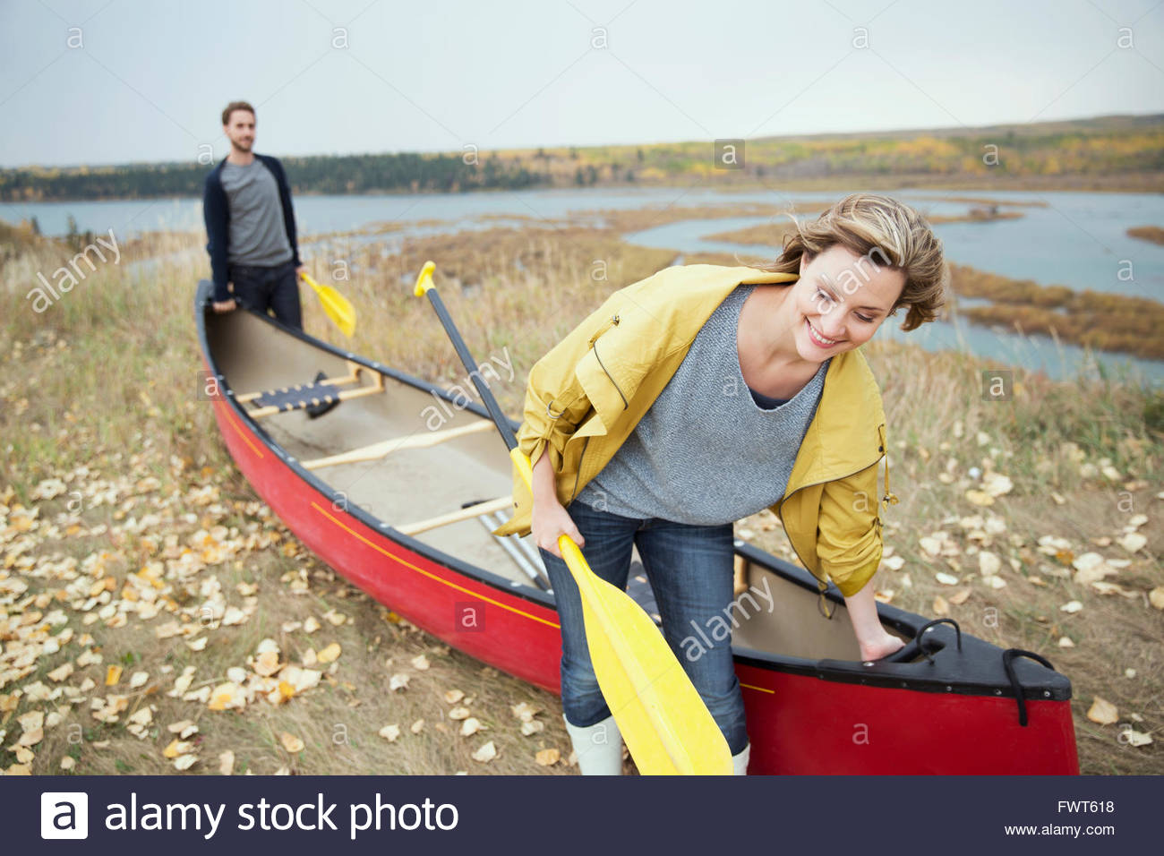 Couple carrying canoe by water Stock Photo - Alamy
