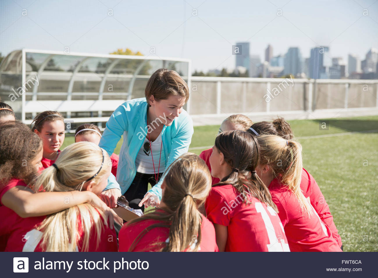Coach giving advice to girls soccer team Stock Photo - Alamy