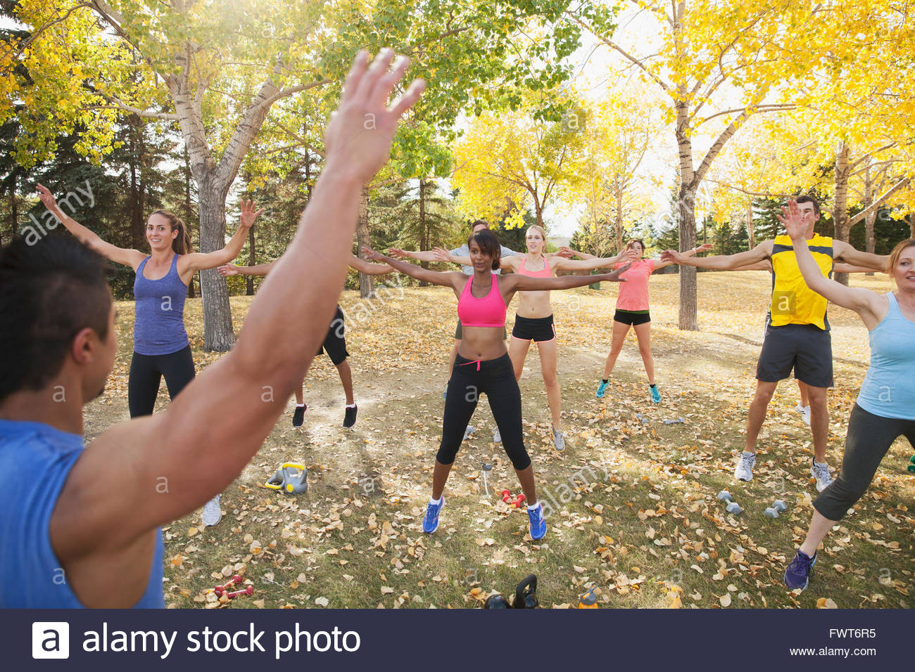 Coach leading outdoor fitness class Stock Photo - Alamy