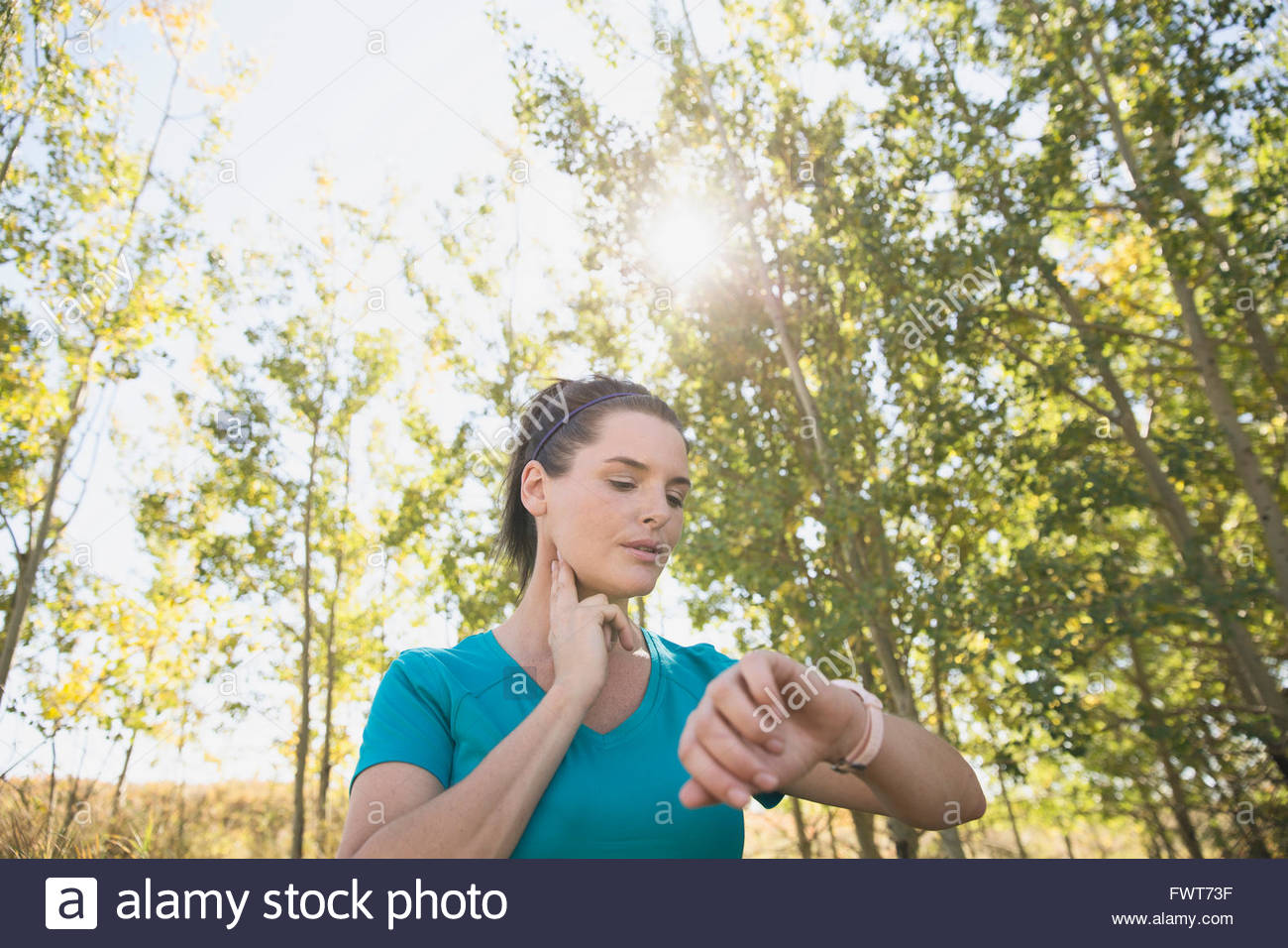 Woman stopping to check her heart rate during run Stock Photo - Alamy