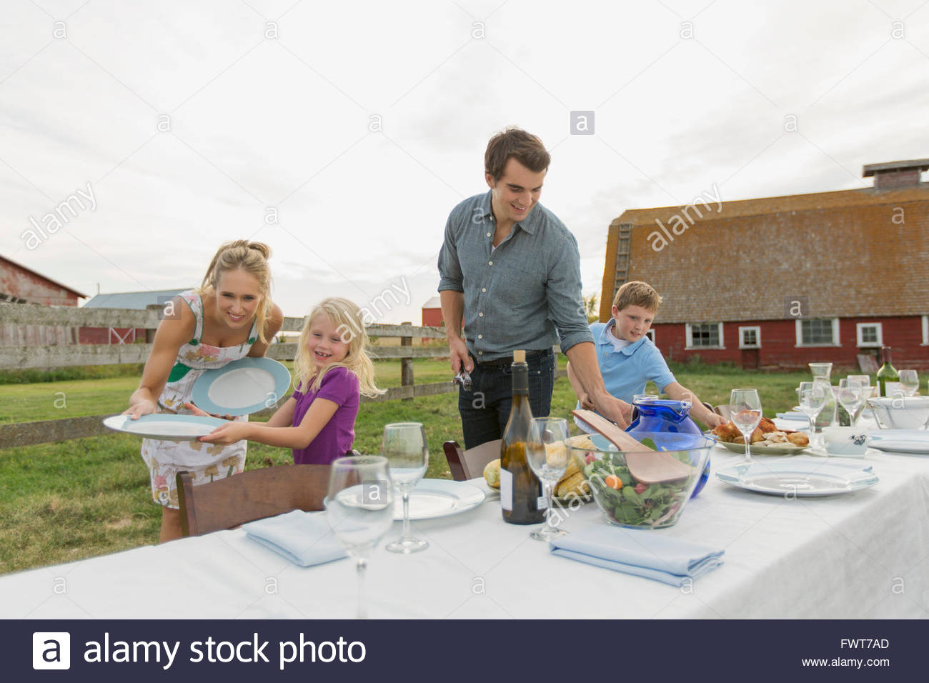 Young family setting table for outdoor dinner Stock Photo - Alamy