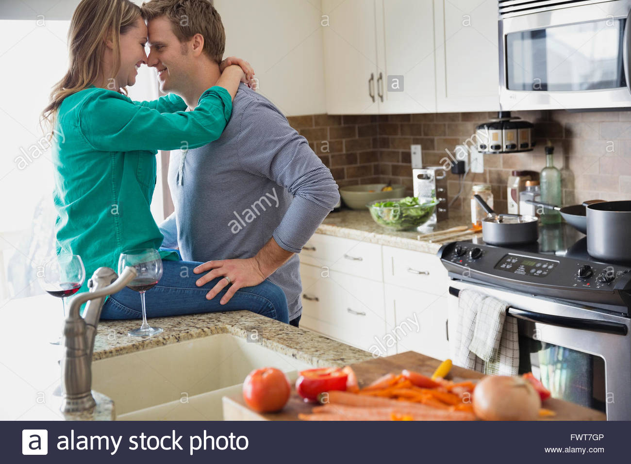 Couple being affectionate in kitchen while preparing dinner Stock Photo ...