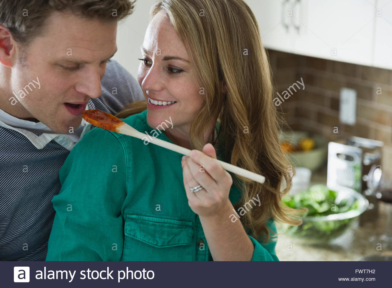 Woman offering husband a taste test from spoon Stock Photo - Alamy