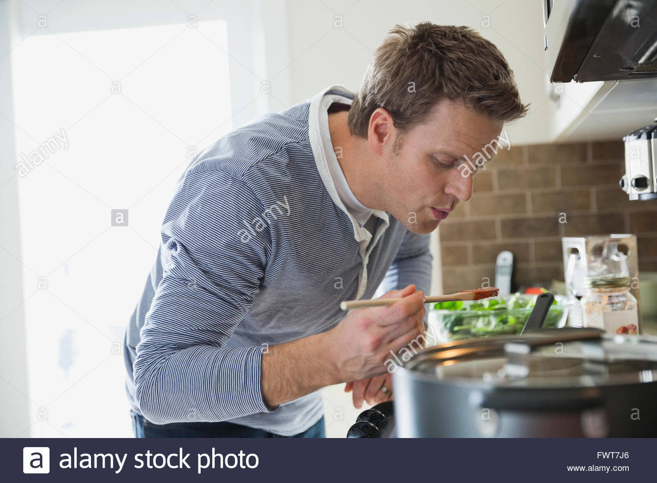 Mid adult man taste testing sauce in domestic kitchen Stock Photo - Alamy